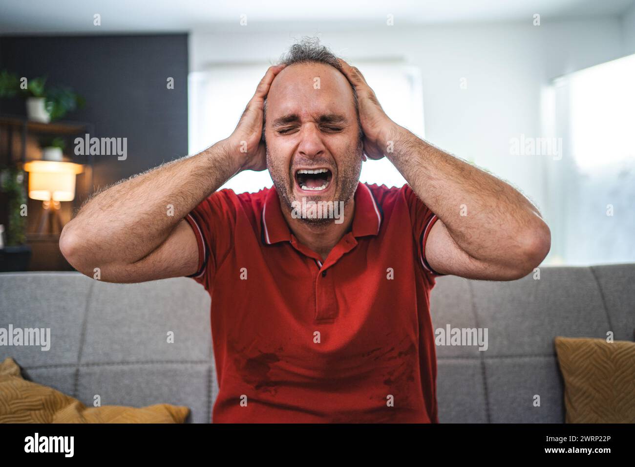 Man sitting alone at home looking sad and distraught Stock Photo - Alamy