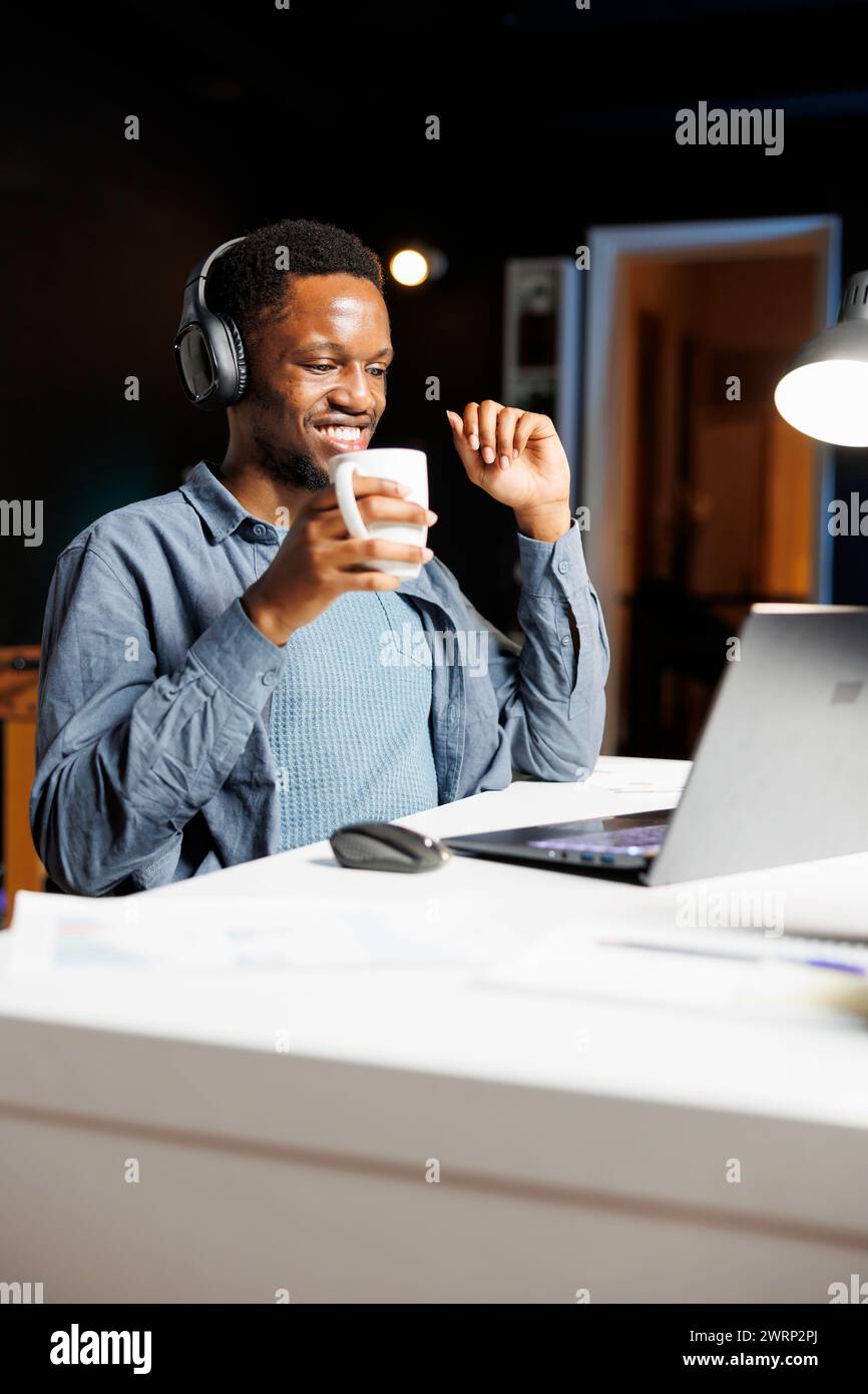 African american guy solving economy tasks online, having fun listening ...