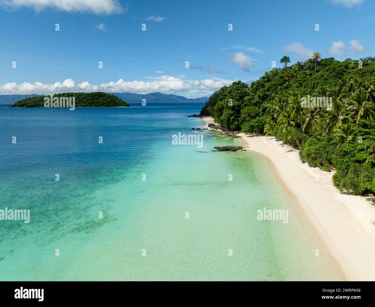 Boat over clear sea water in Tiamban Beach. Blue sky and clouds ...