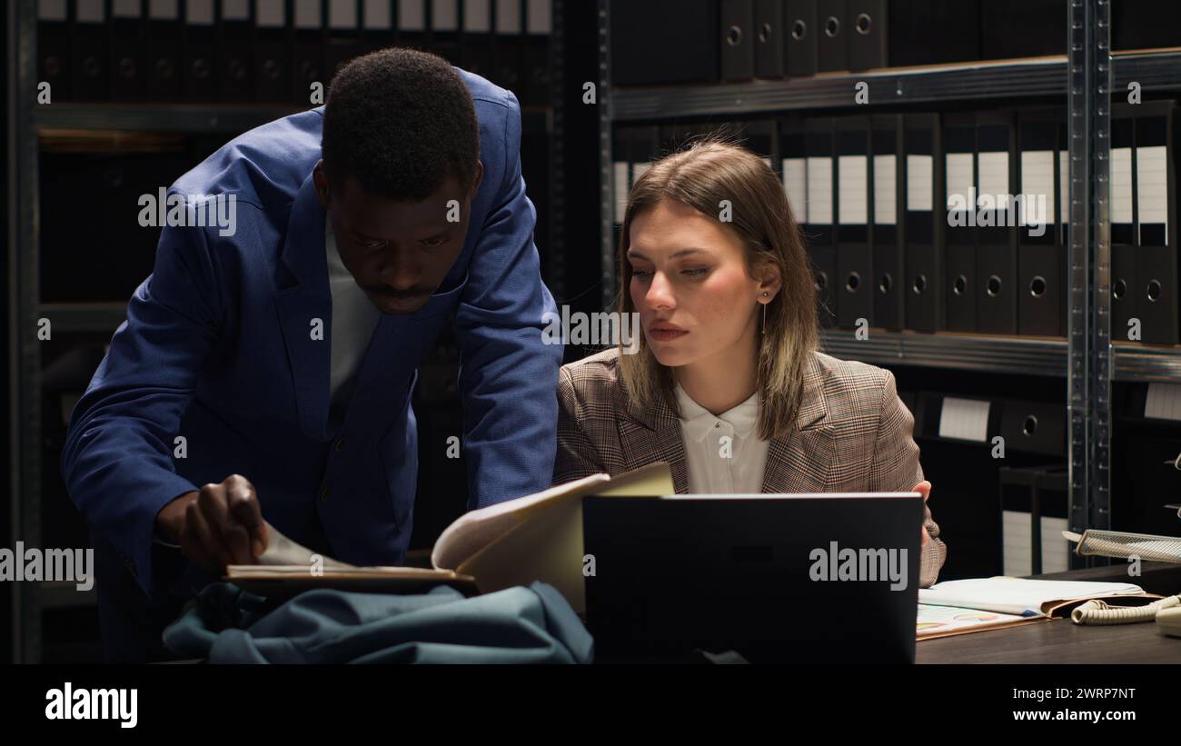 African american inspector carrying files and evidence to female ...
