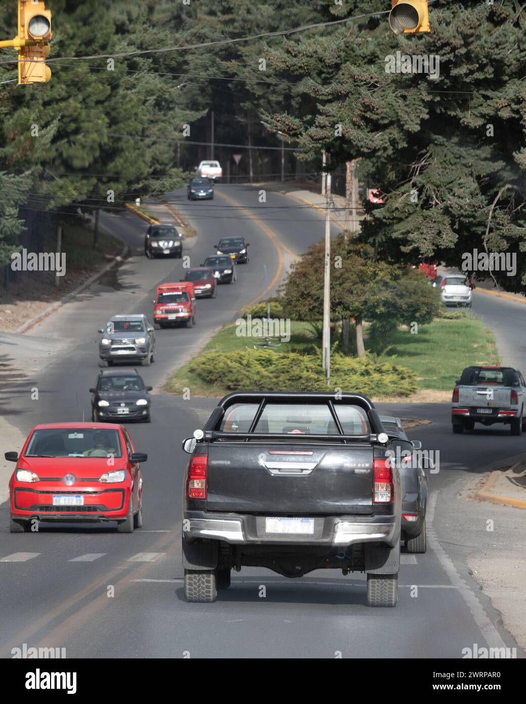Many multicolored cars driving on a curved two way road in an urban ...