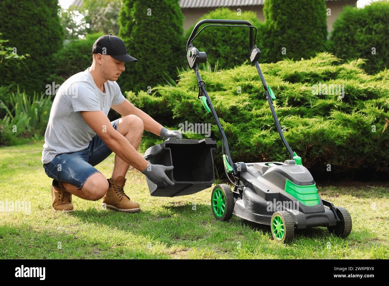 Cleaning lawn mower. Young man detaching grass catcher from device in ...