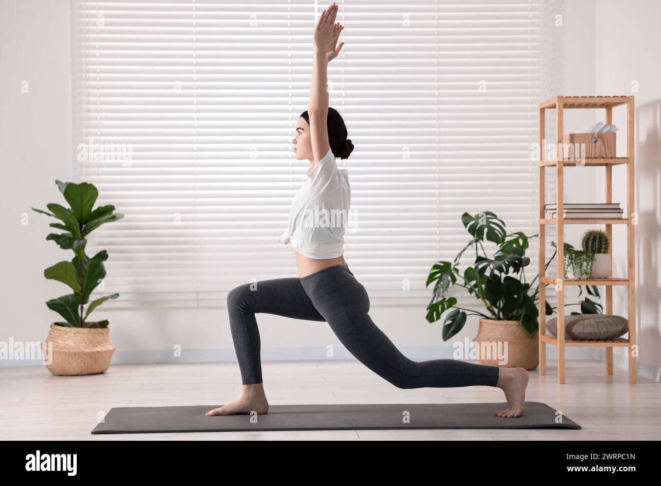 Girl practicing crescent asana on mat in yoga studio. High lunge pose ...