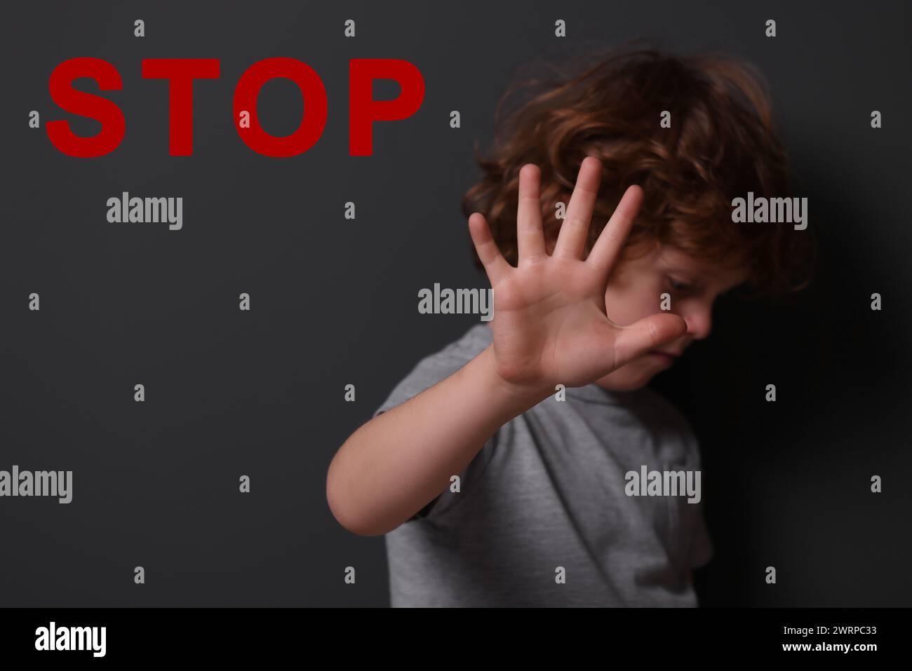 No child abuse. Boy making stop gesture near grey wall, selective focus ...