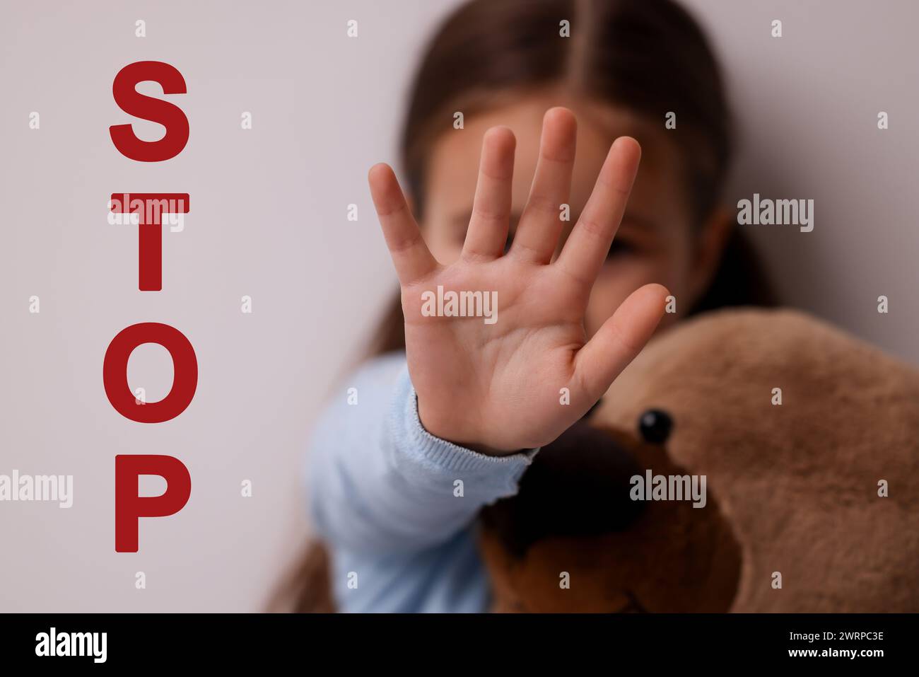 No child abuse. Little girl making stop gesture on light background ...