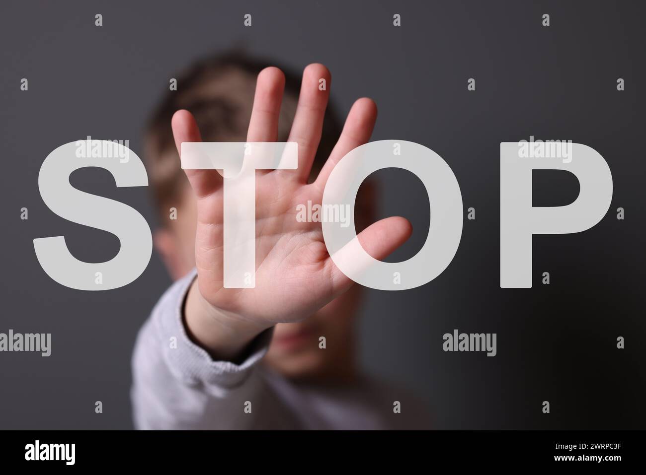No child abuse. Boy making stop gesture on grey background, selective ...