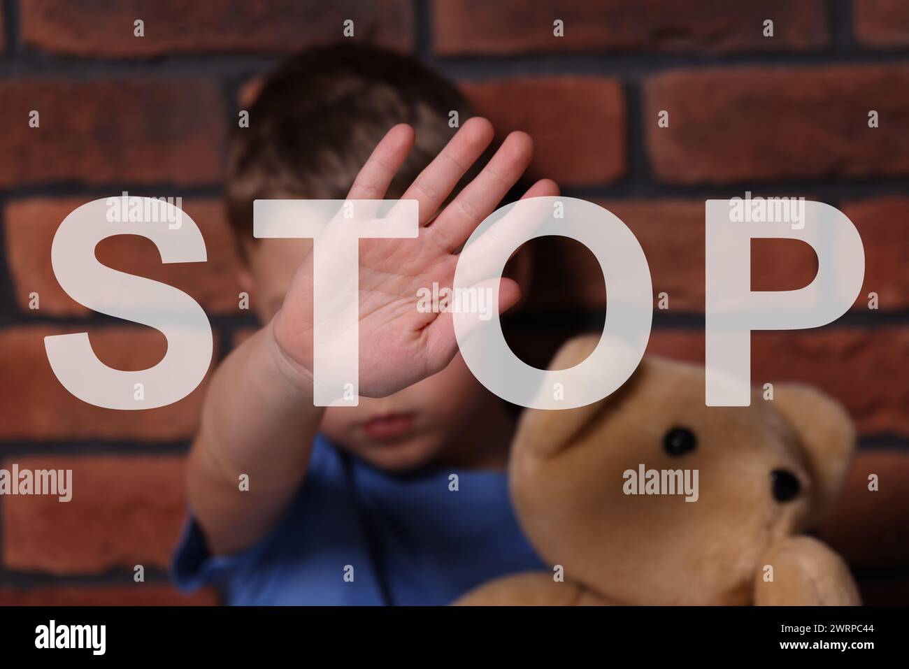 No child abuse. Boy with teddy bear making stop gesture near brick wall ...