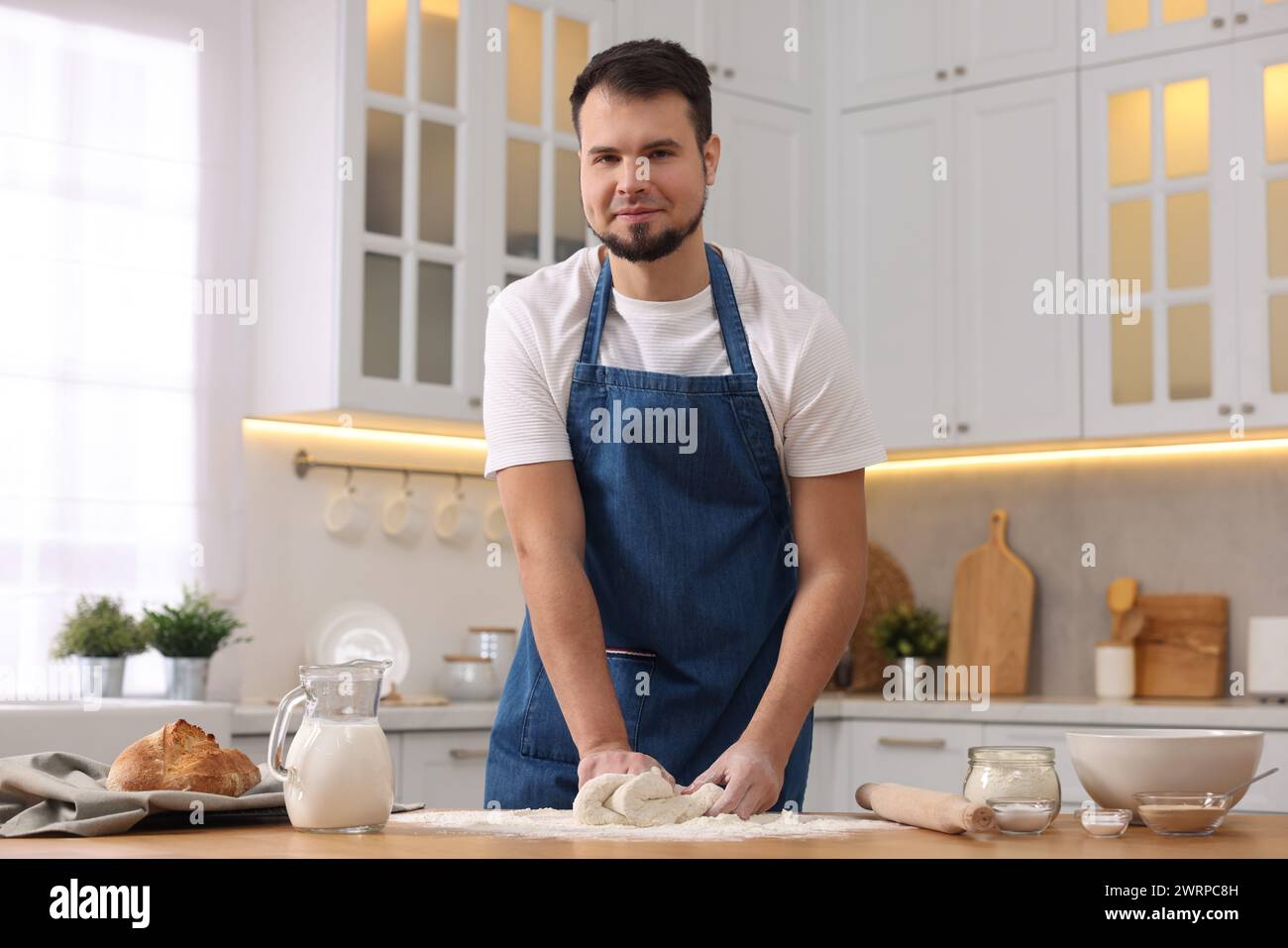 Making bread. Man kneading dough at wooden table in kitchen Stock Photo ...