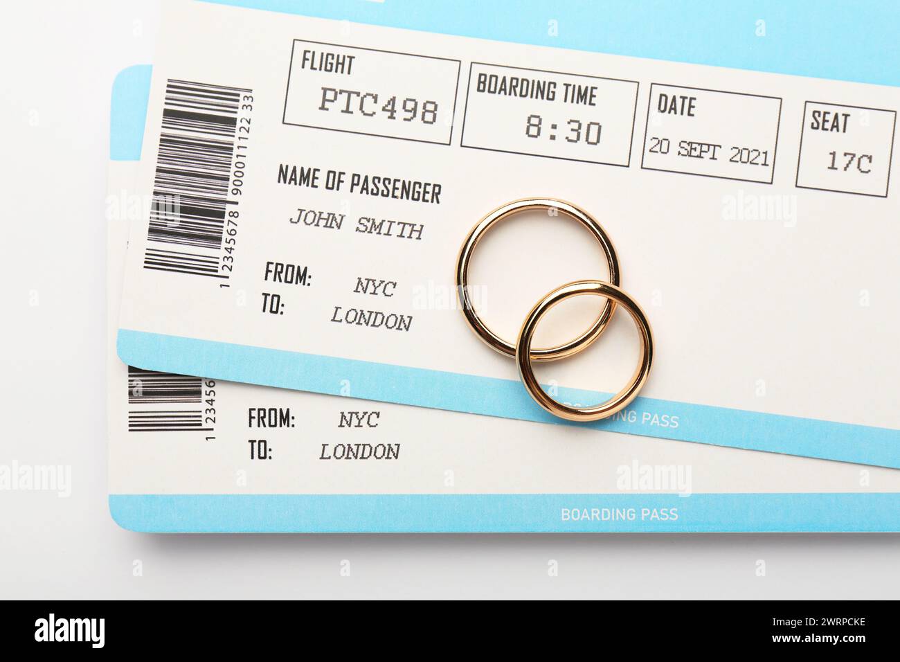Honeymoon concept. Plane tickets and two golden rings on white ...