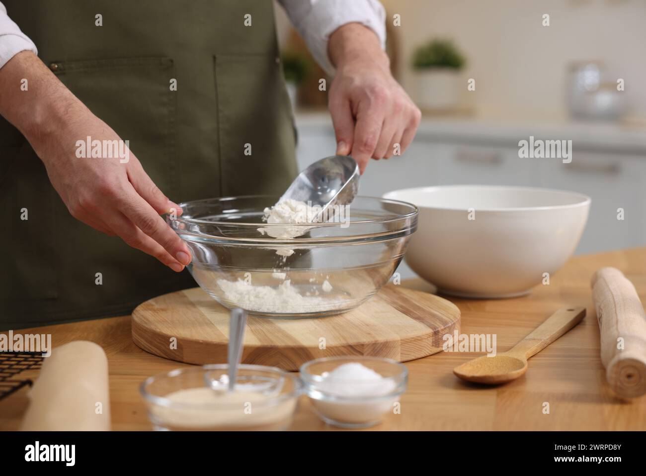 Making bread. Man putting flour into bowl at wooden table in kitchen ...