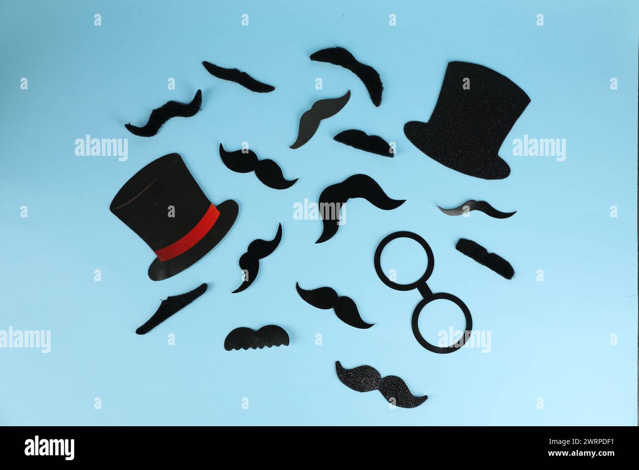 Fake mustaches, hats and glasses on light blue background, flat lay ...