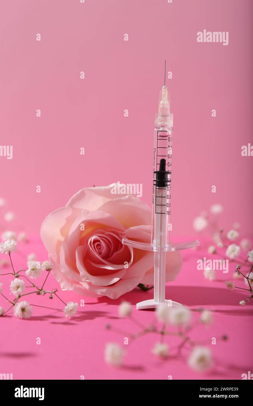 Cosmetology. Medical syringe, rose and gypsophila flowers on pink ...