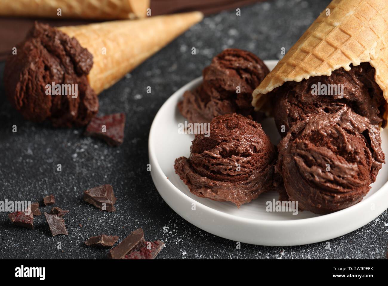 Tasty ice cream scoops, chocolate crumbs and waffle cones on dark ...