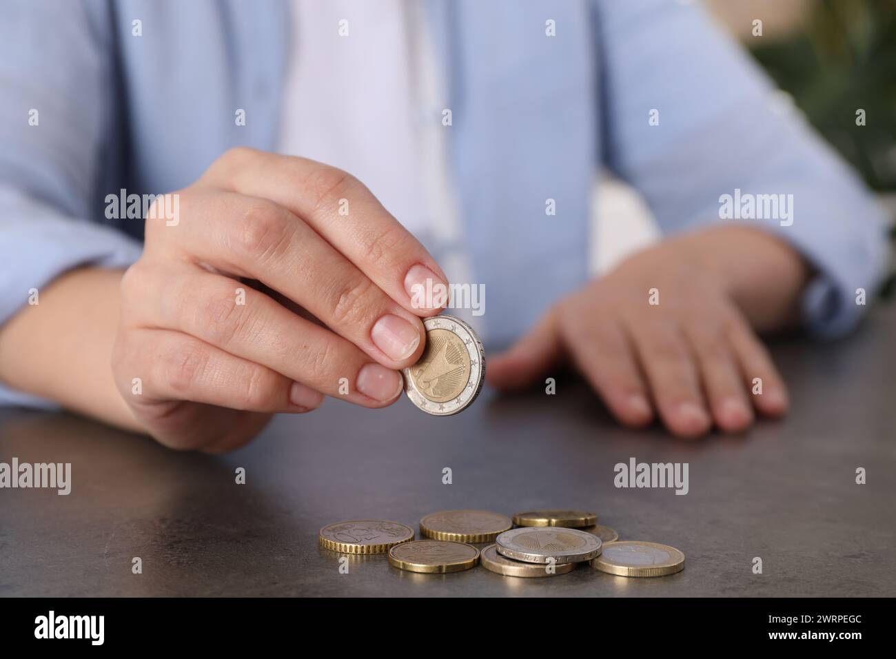 Poor woman counting coins at grey table indoors, closeup Stock Photo ...