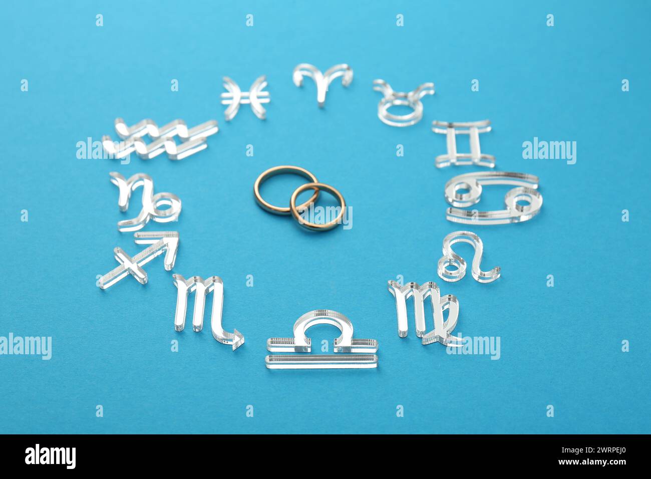 Zodiac signs and wedding rings on light blue background, closeup Stock ...