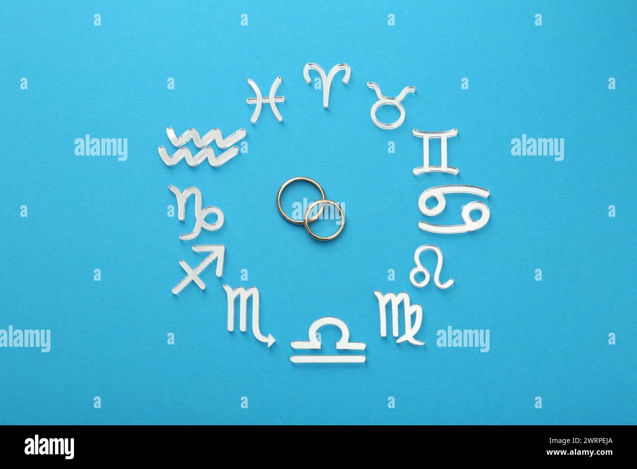 Zodiac signs and wedding rings on light blue background, flat lay Stock ...