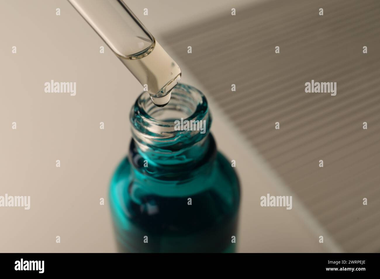 Dripping moisturizing serum from pipette into bottle on light ...