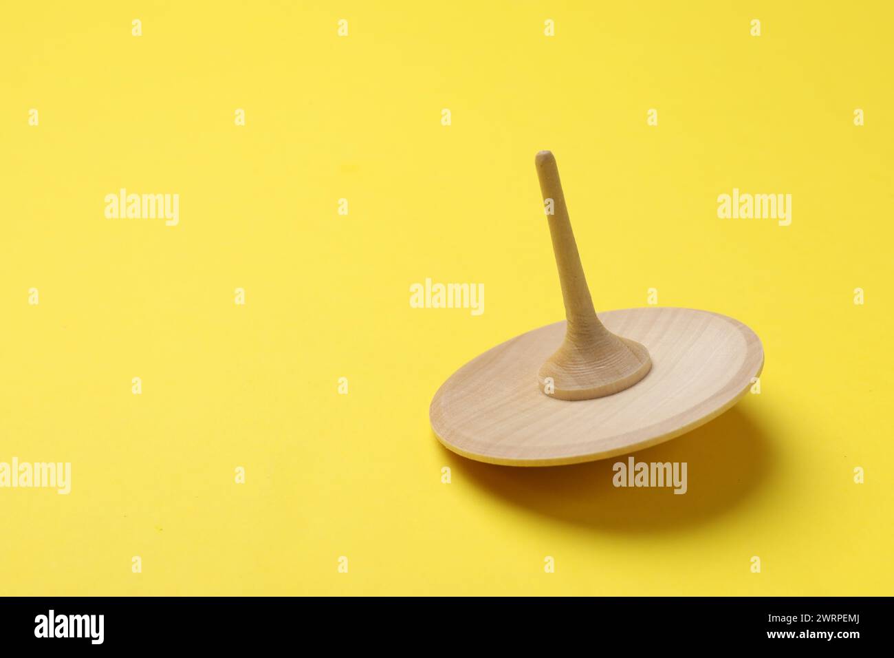 One wooden spinning top on yellow background, space for text Stock ...