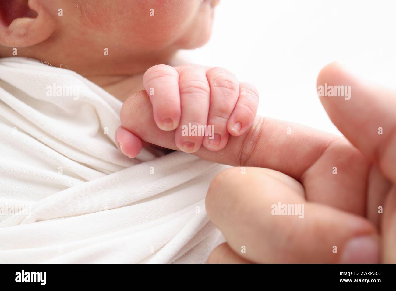 Close-up of baby's hand, head, ear and palm of mother. Newborn baby ...