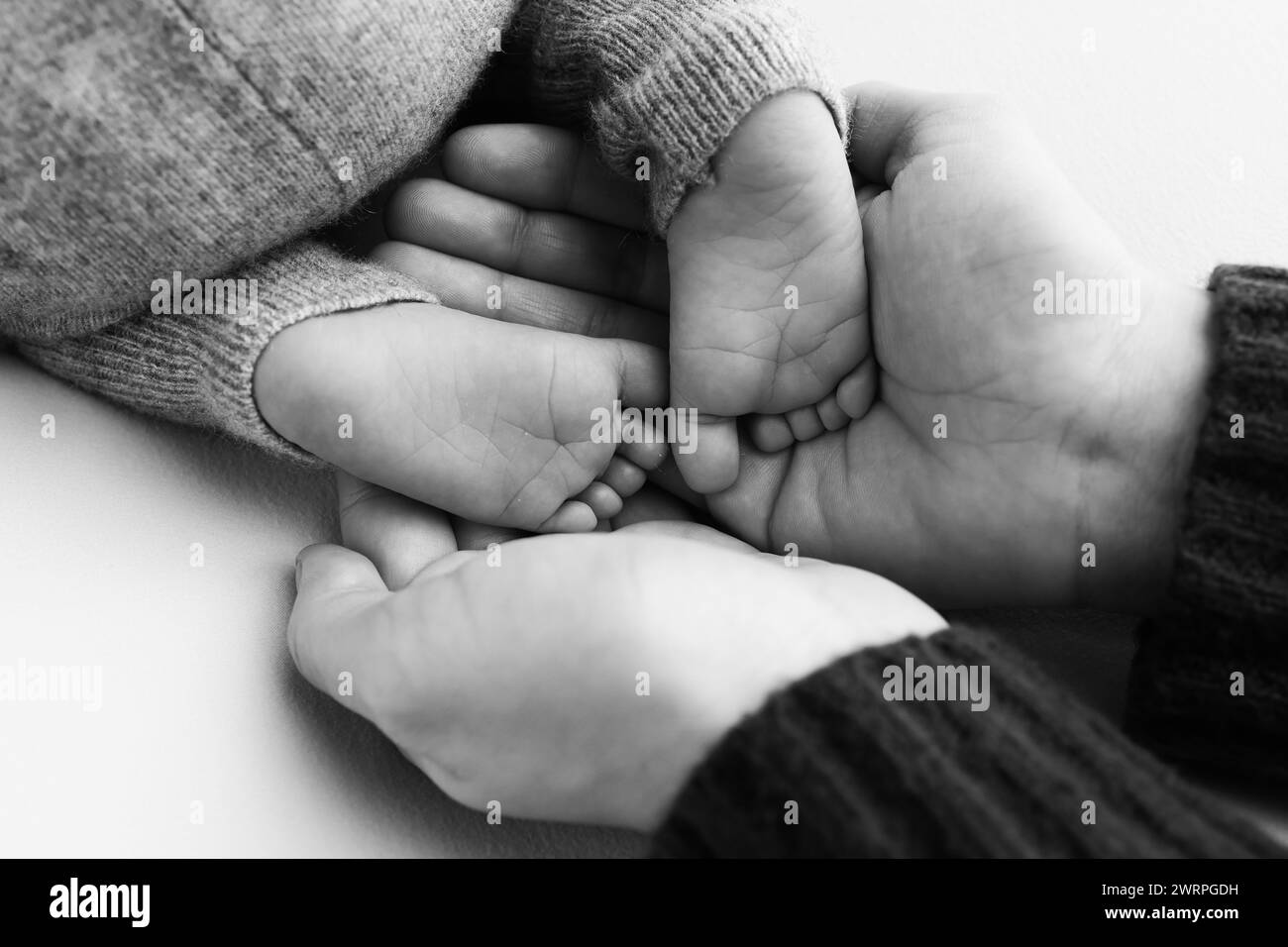 The palms of the father, the mother are holding the foot of the newborn ...