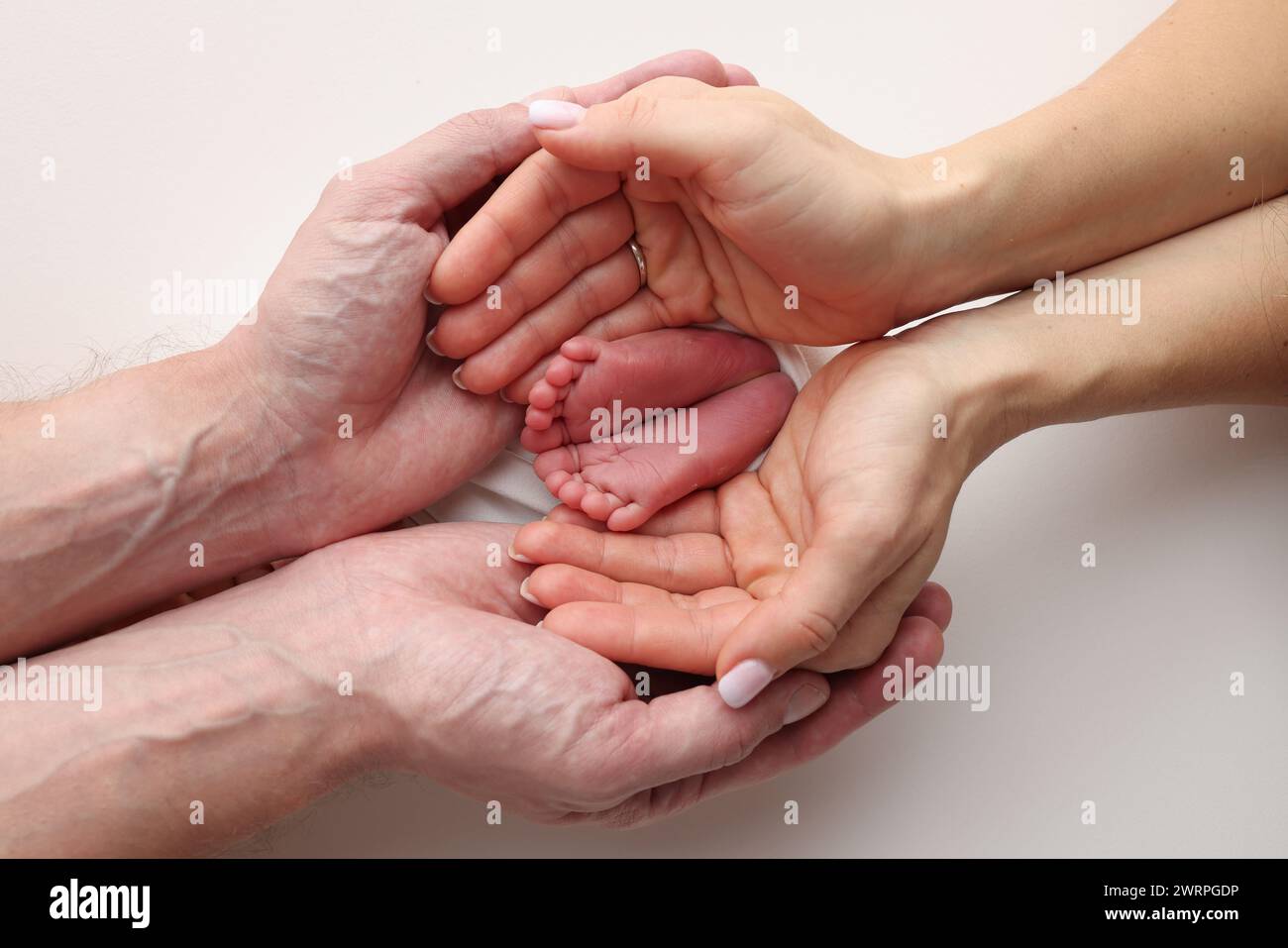 The palms of the father, the mother are holding the foot of the newborn ...
