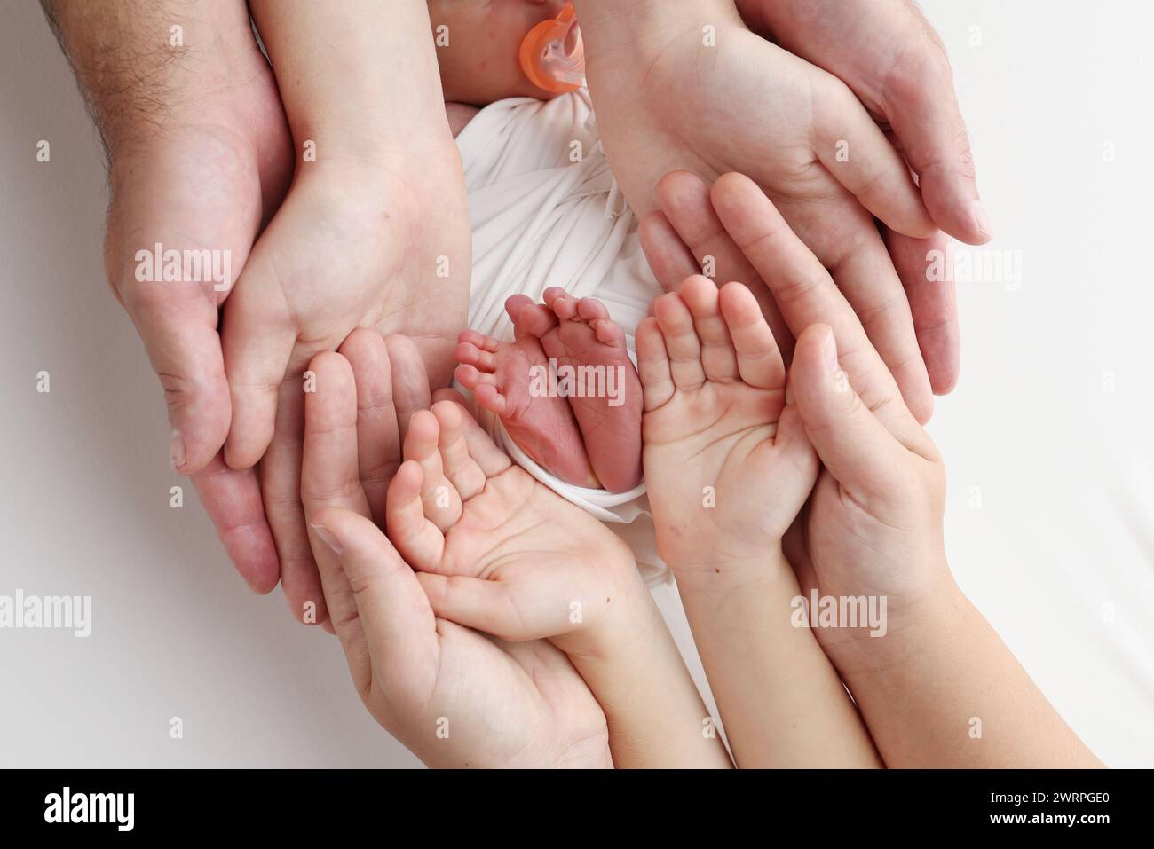 The palms of the father, the mother are holding the foot of the newborn ...