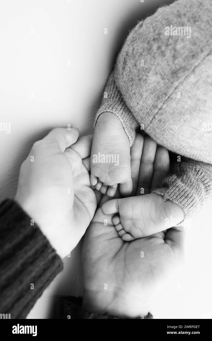 The palms of the father, the mother are holding the foot of the newborn ...