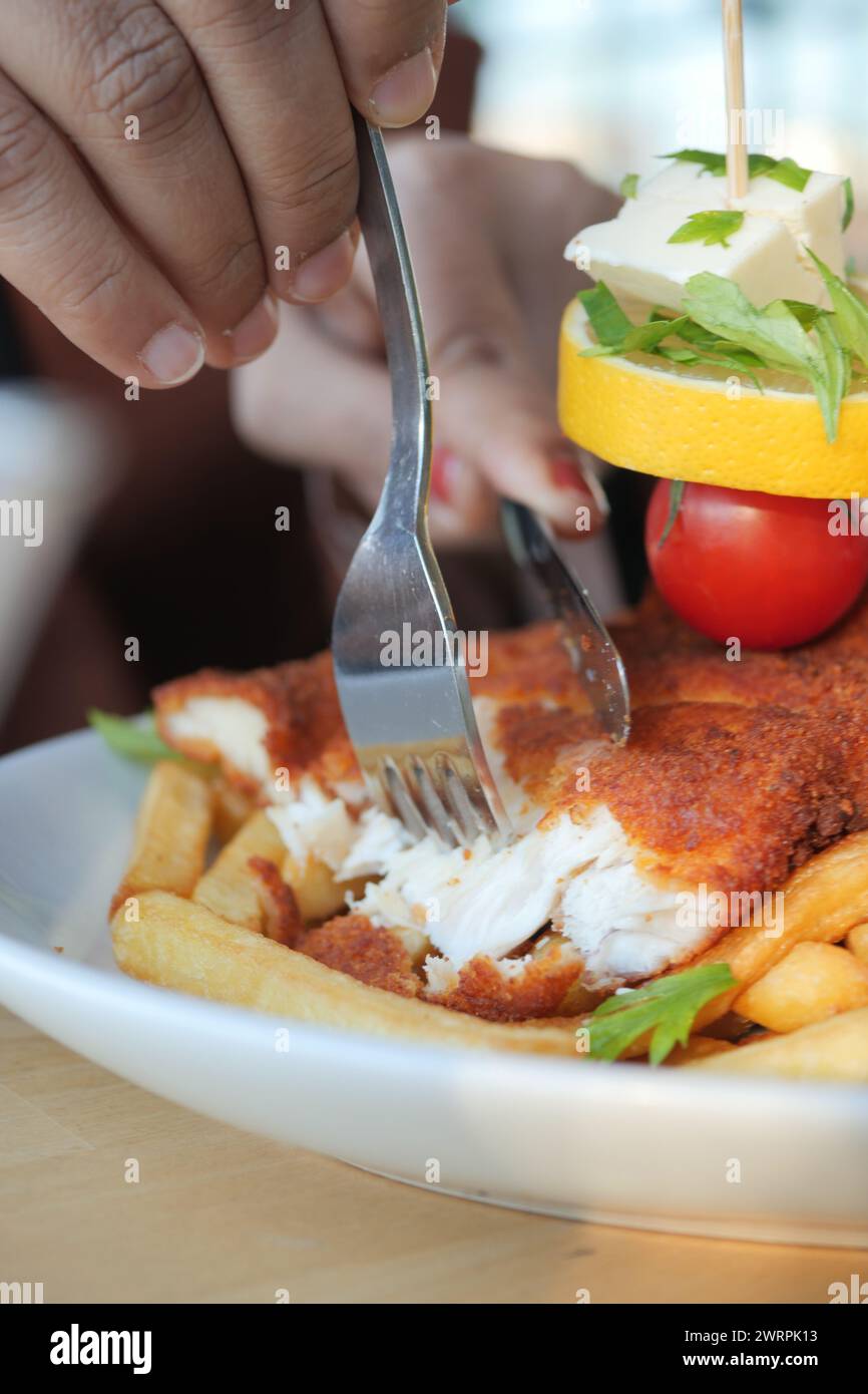women eating Chicken schnitzel served with potato chips Stock Photo - Alamy