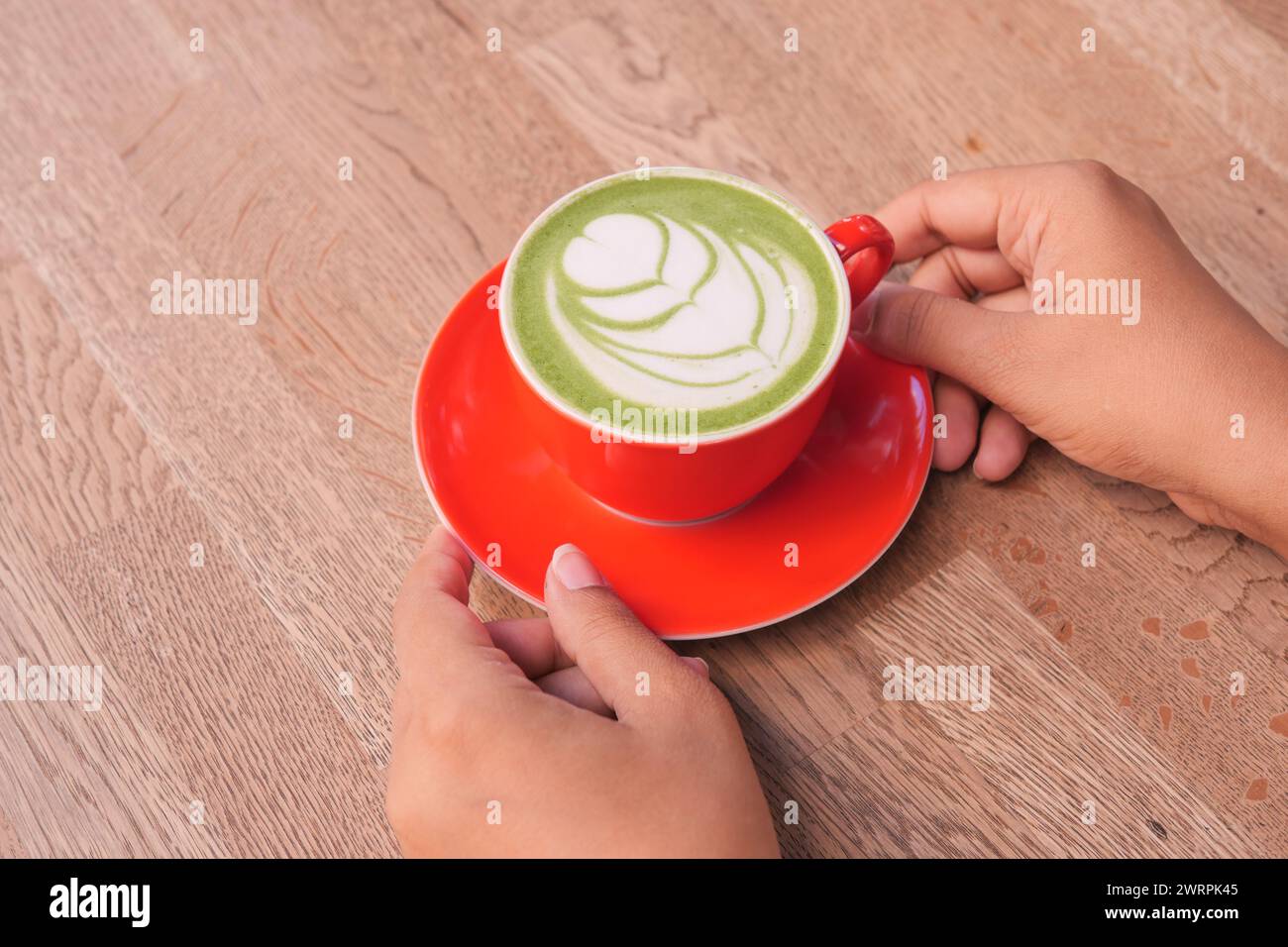 hand holding a matcha latte in a red color cup on table Stock Photo - Alamy