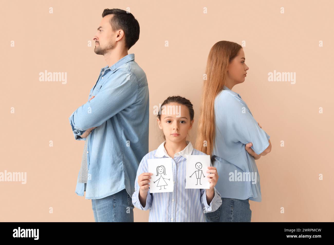 Sad little girl with torn drawing of family and her parents on beige ...