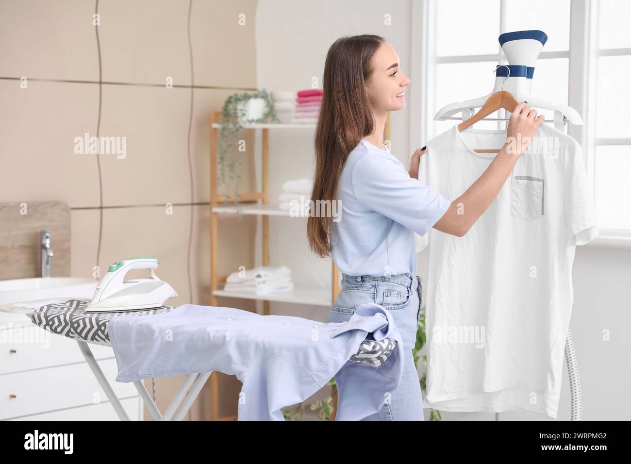 Pretty young woman with modern garment steamer in laundry room Stock ...