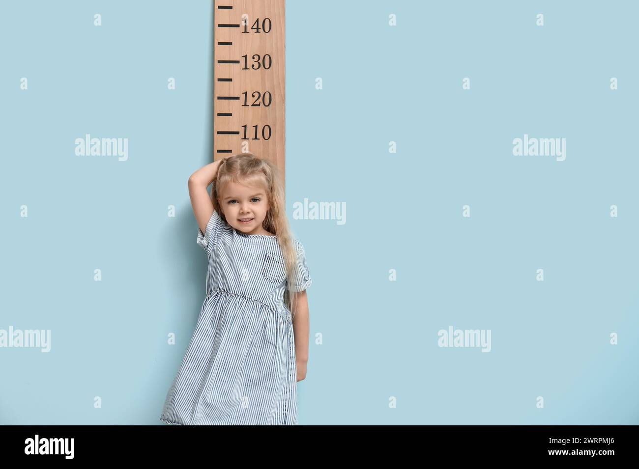 Cute little girl measuring height on blue background Stock Photo - Alamy