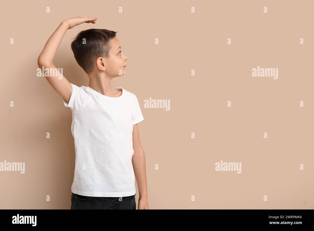 Cute little boy measuring height on beige background Stock Photo - Alamy
