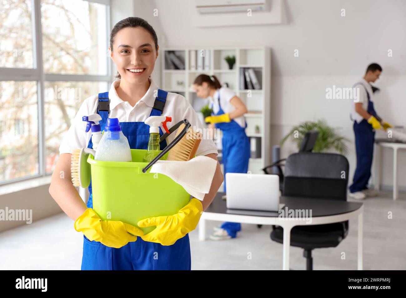 Female janitor with bucket of cleaning supplies in office Stock Photo ...