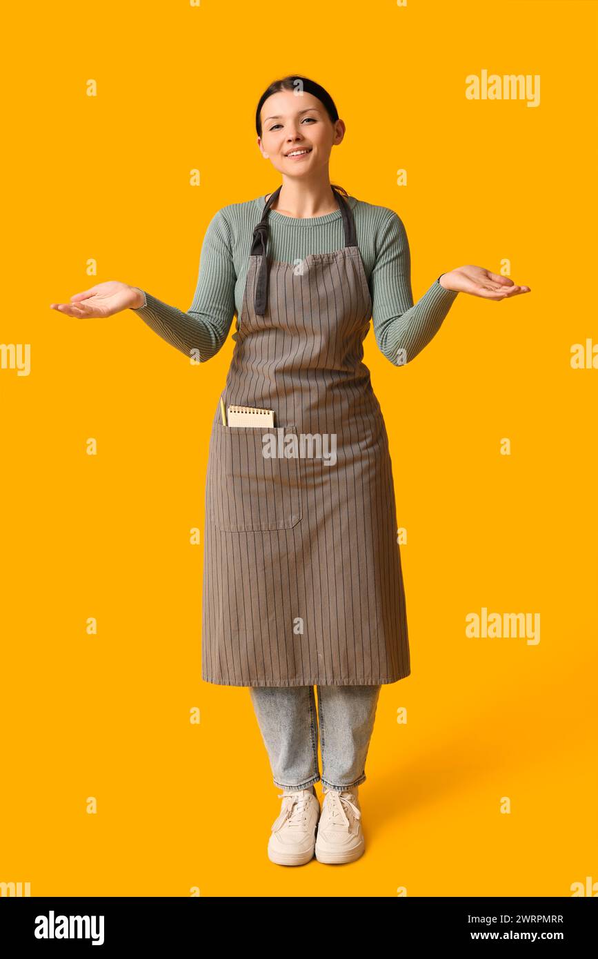 Beautiful young waitress on yellow background Stock Photo - Alamy