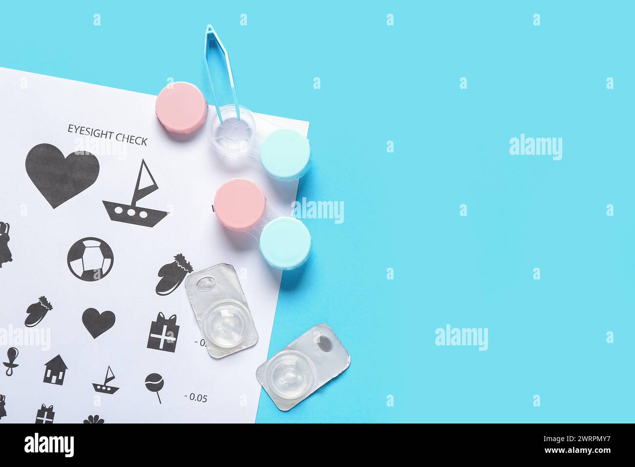 Eye test chart with tweezers, containers and contact lenses on blue ...