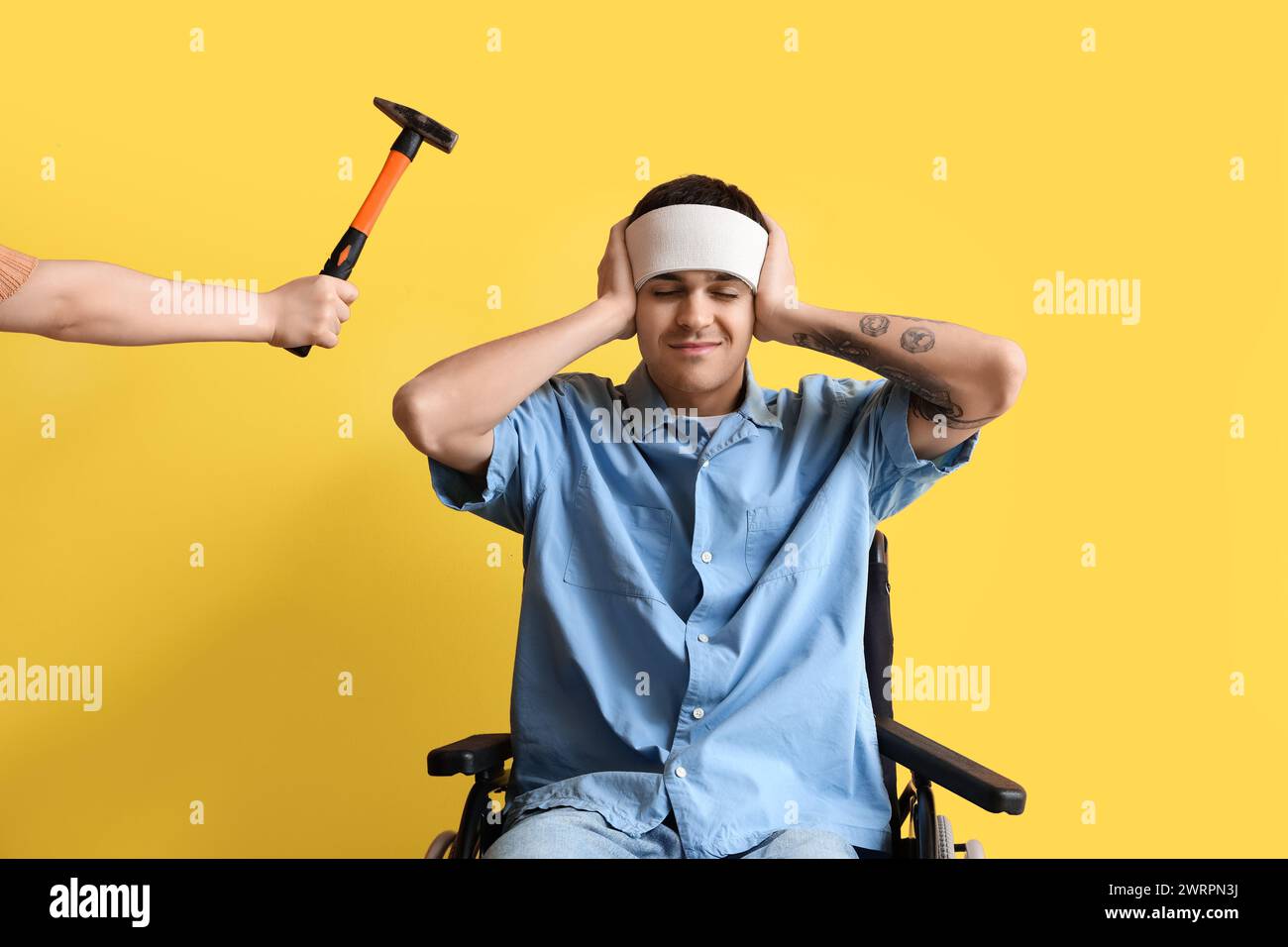 Young man with brain concussion in wheelchair and hammer on yellow ...