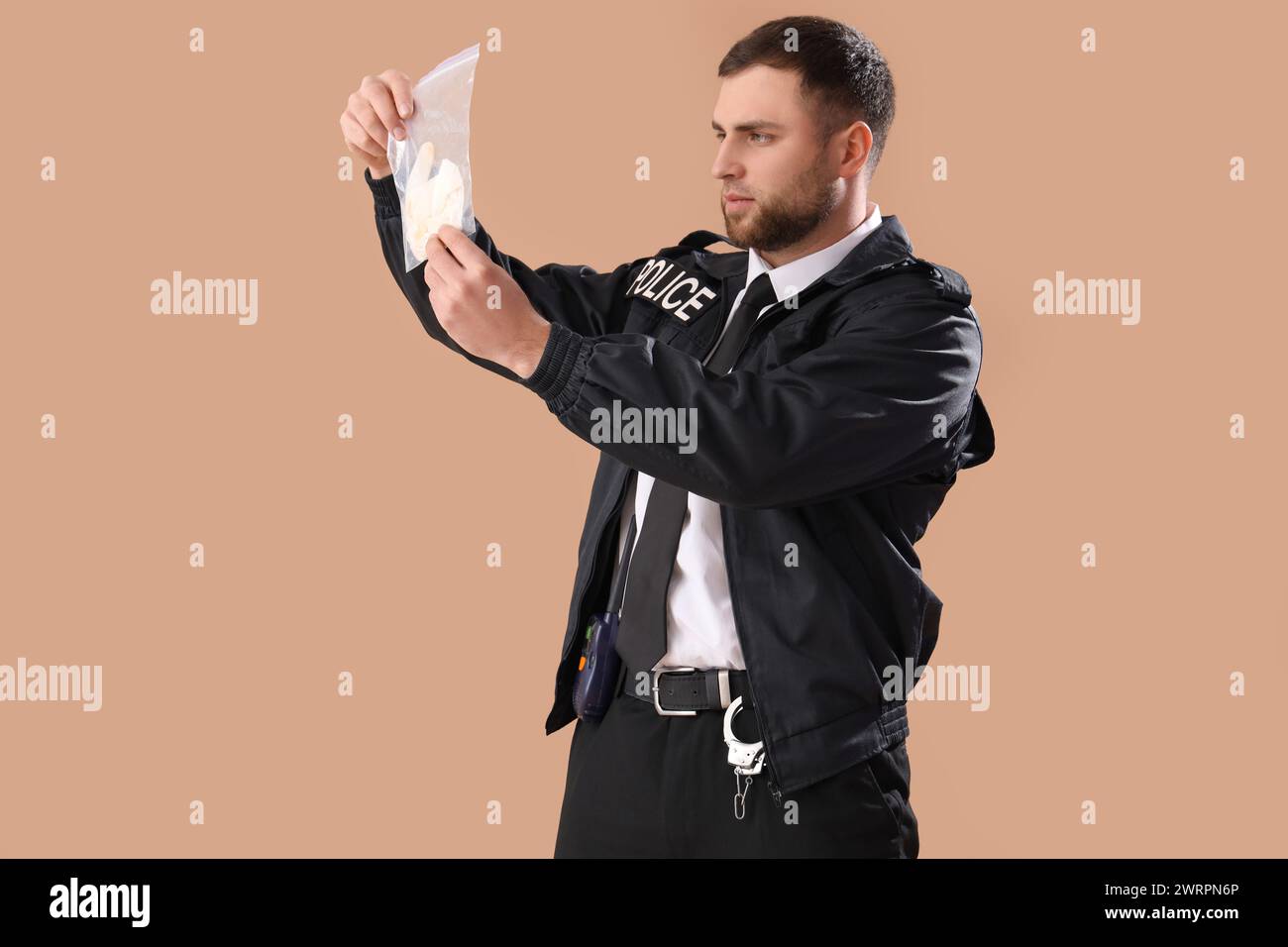 Male police officer with evidence on beige background Stock Photo - Alamy