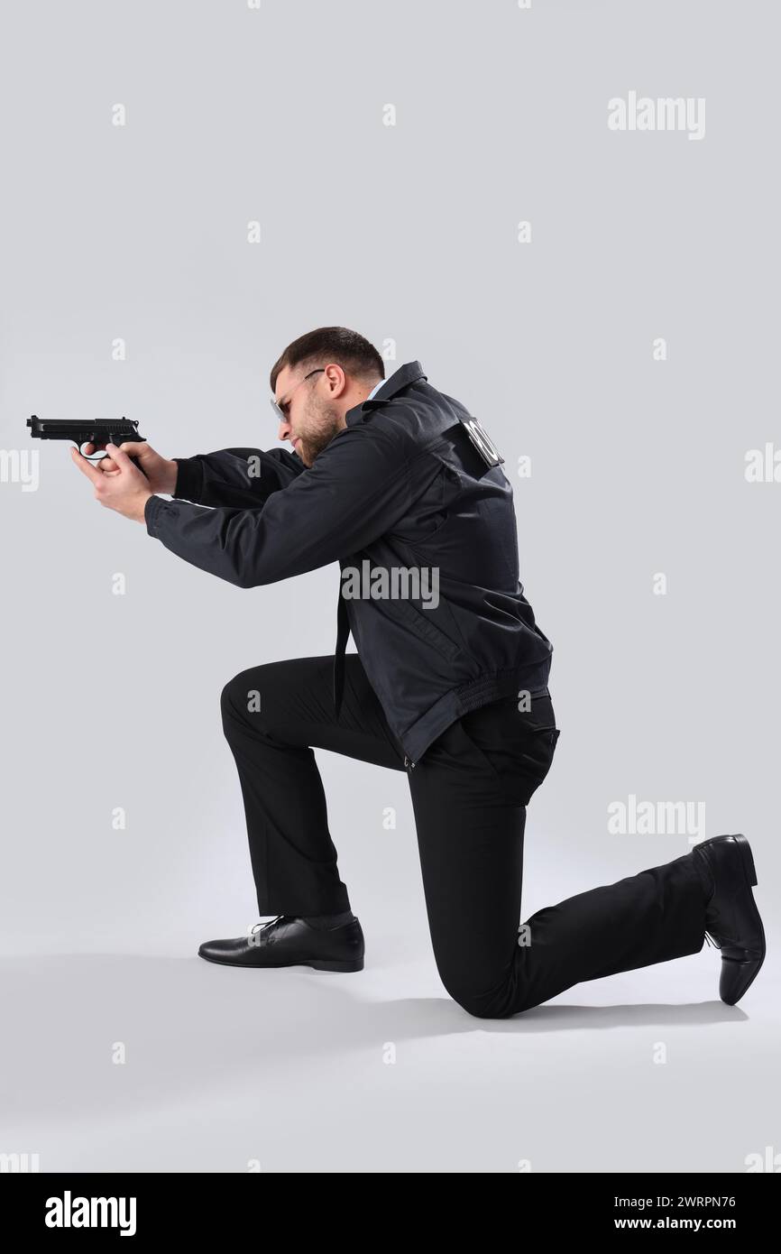 Male police officer with gun on grey background Stock Photo - Alamy