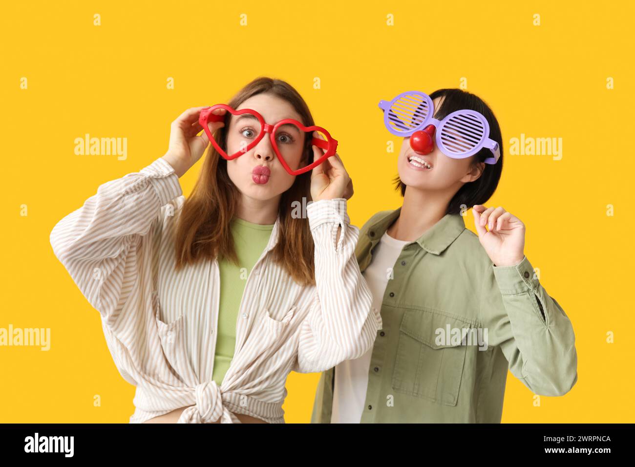 Beautiful young women in funny disguise on yellow background. April ...