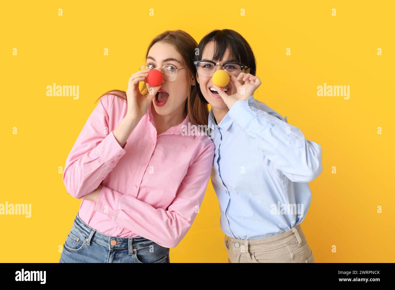 Beautiful young shocked women with funny clown noses on yellow ...