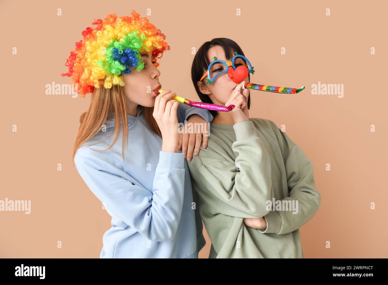 Beautiful young women in funny clown disguise with party whistles on ...
