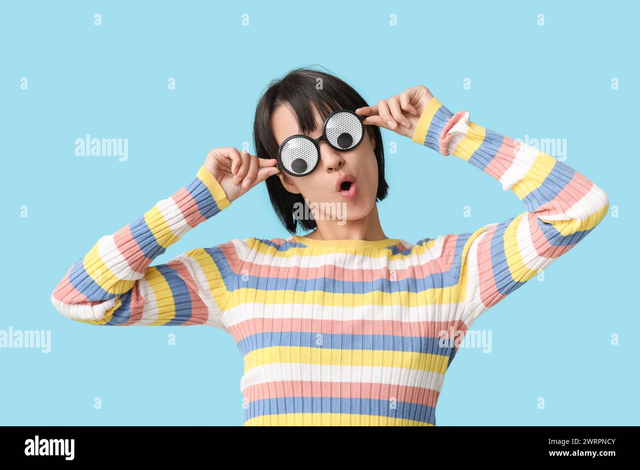 Beautiful young shocked woman in funny disguise on blue background ...