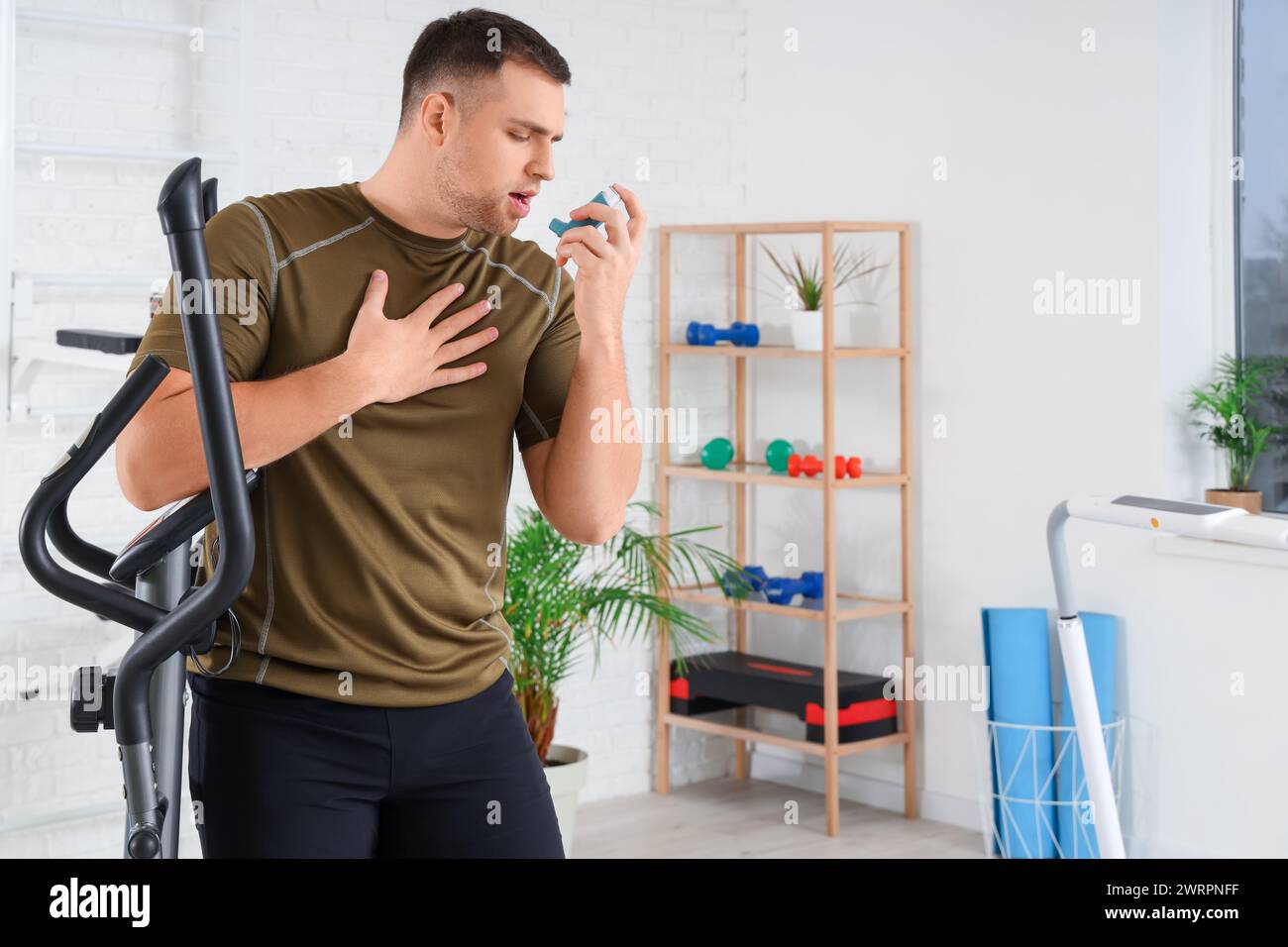 Sporty young man using inhaler in gym Stock Photo - Alamy