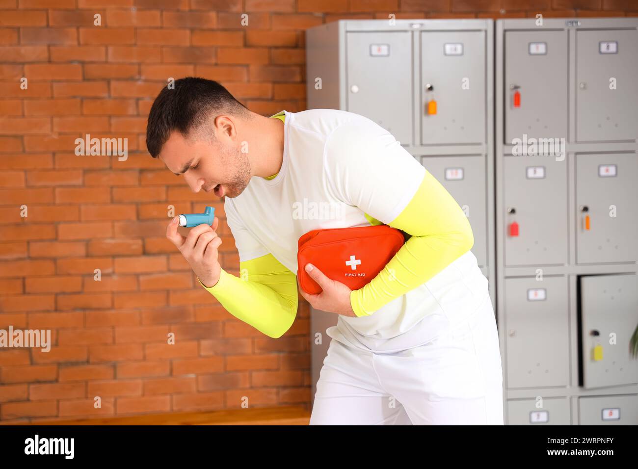 Sporty young man with first aid kit using inhaler in gym Stock Photo ...
