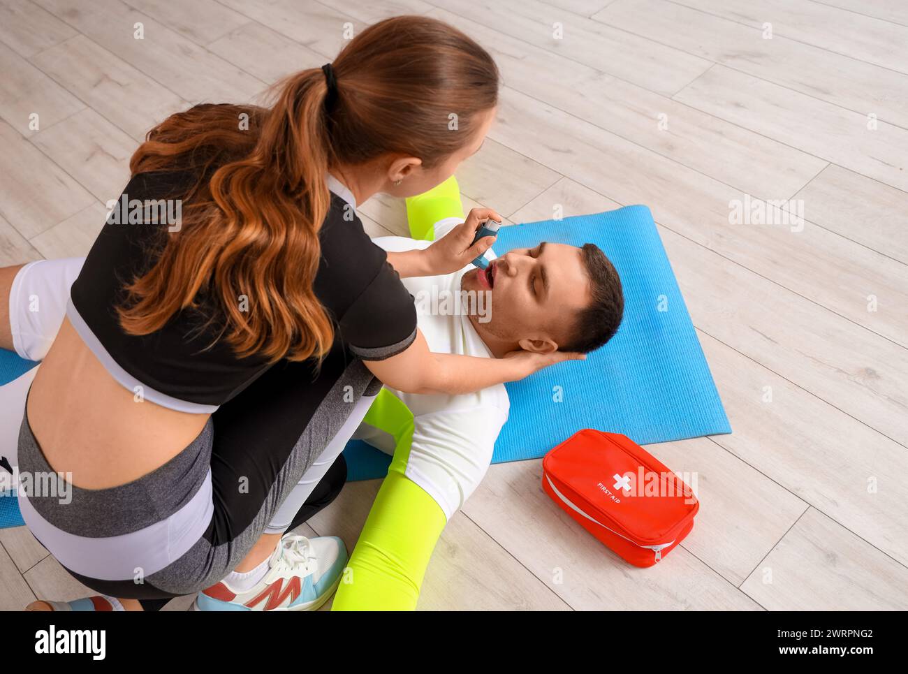 Female trainer with asthma inhaler giving man first aid in gym Stock ...