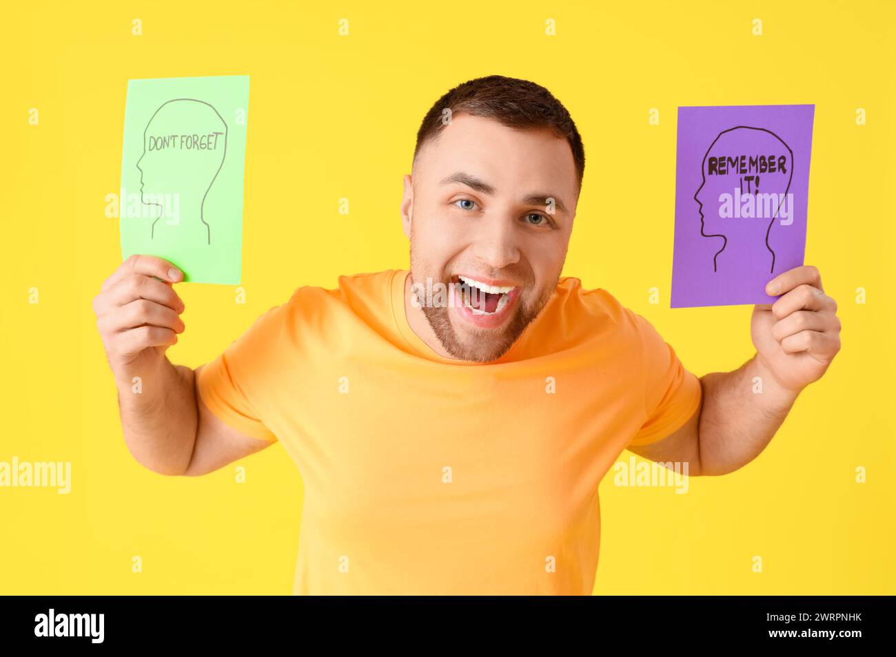 Young man with reminders on yellow background Stock Photo - Alamy