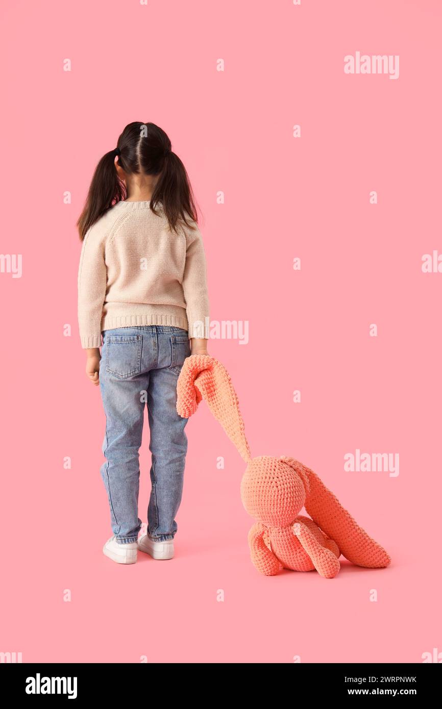 Little girl with autistic disorder and toy bunny on pink background ...