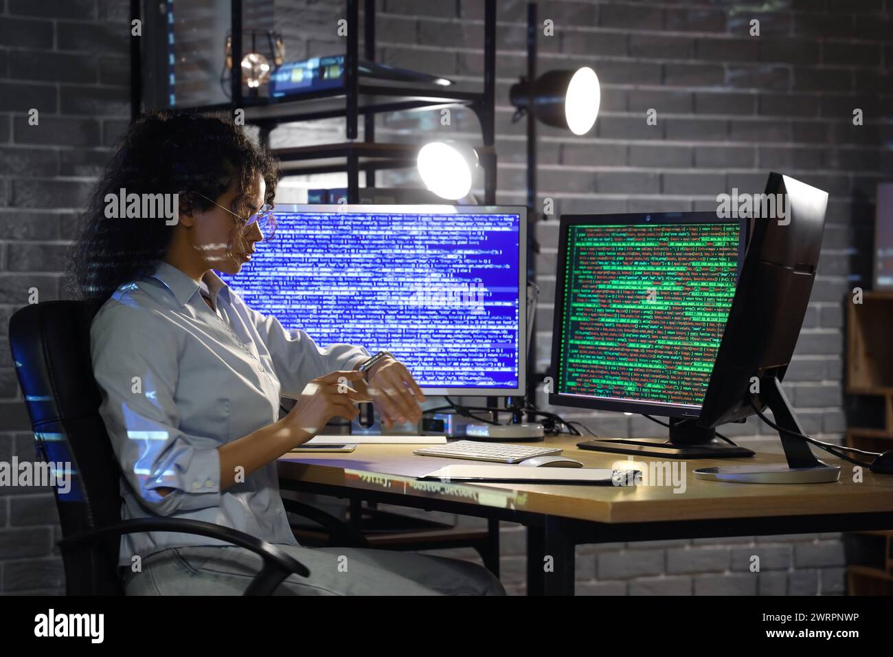 Female African-American programmer looking at smartwatch in office ...