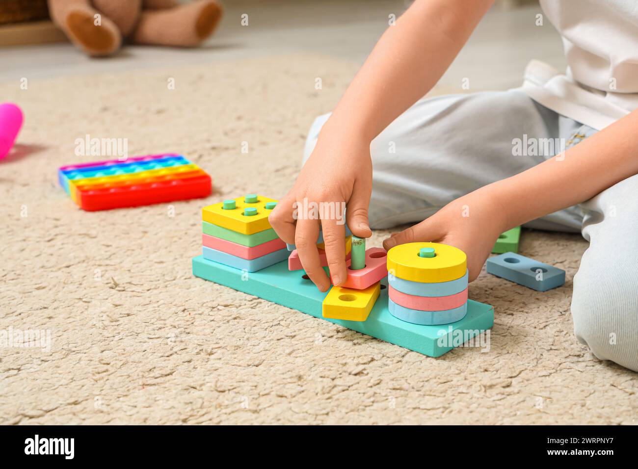 Little girl playing with building blocks at home, closeup. Autistic ...